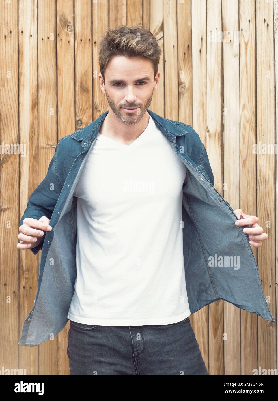 Young handsome man is standing on a light wooden wall background. Guy ...