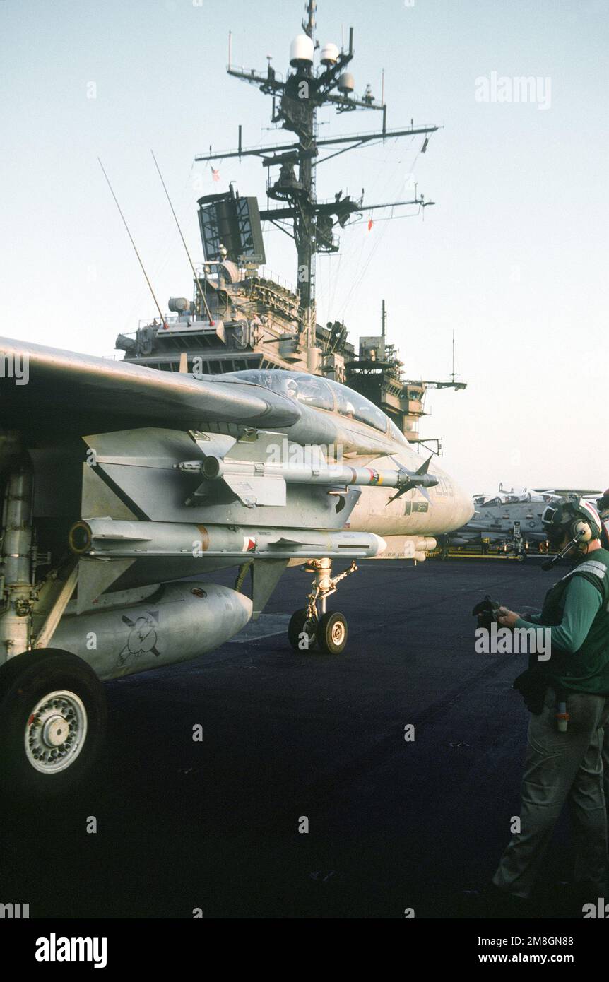 A flight deck crewman approaches a Fighter Squadron 103 (VF-103) F-14B ...