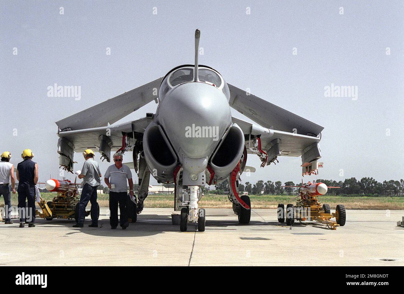 Workers use a weapons loader to position a BQM-74E target drone under a ...