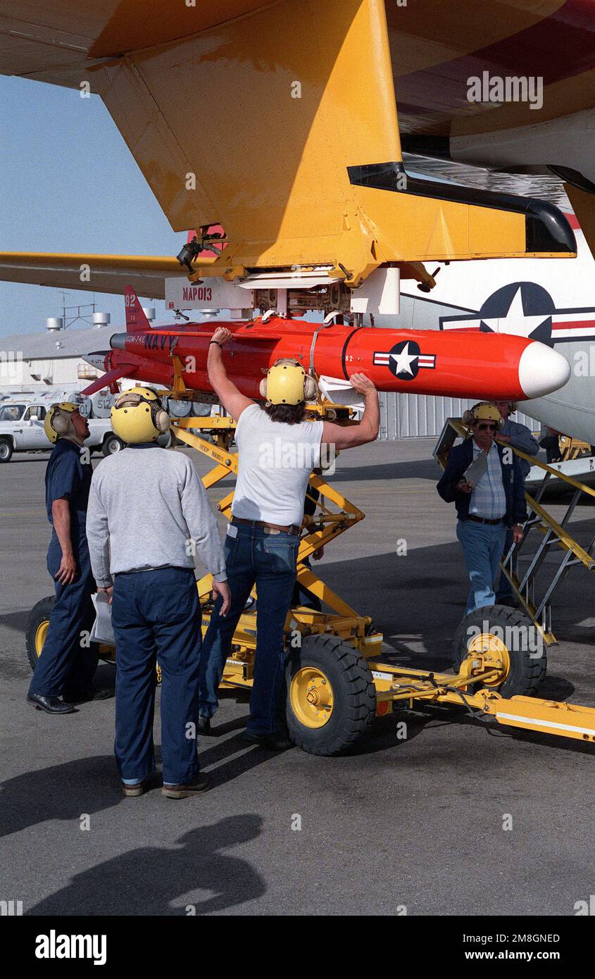 Workers secure a BQM-74E target drone to a wing pylon of a DC-130A ...