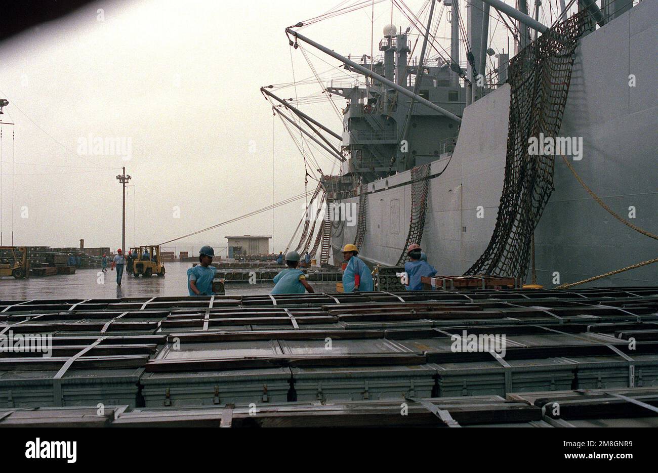 Crates of ammunition line the pier in preparation for loading aboard ...