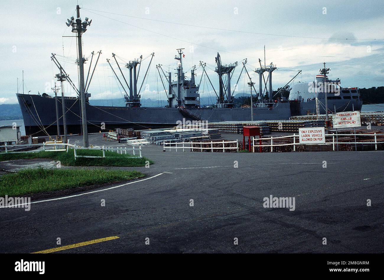 Racks of ordnance line the pier beside the cargo ship BUYER (T-AK-2033 ...
