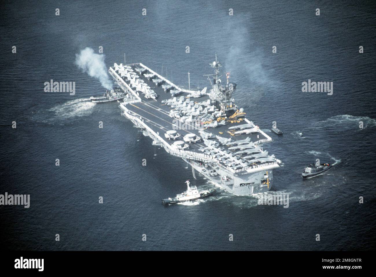 Large harbor tugs encircle the aircraft carrier USS RANGER (CV-61) as ...