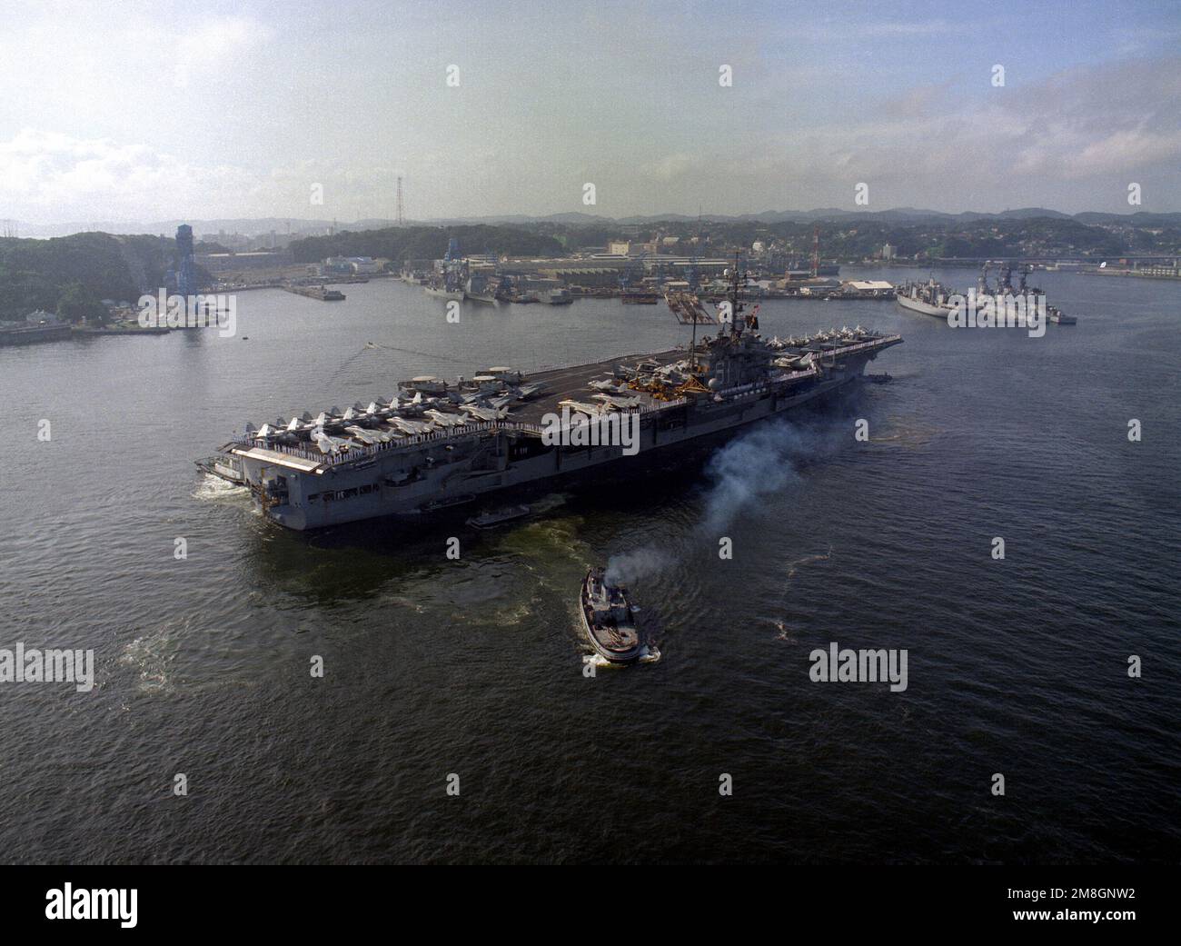 Large harbor tugs maneuver the aircraft carrier USS RANGER (CV-61) into ...
