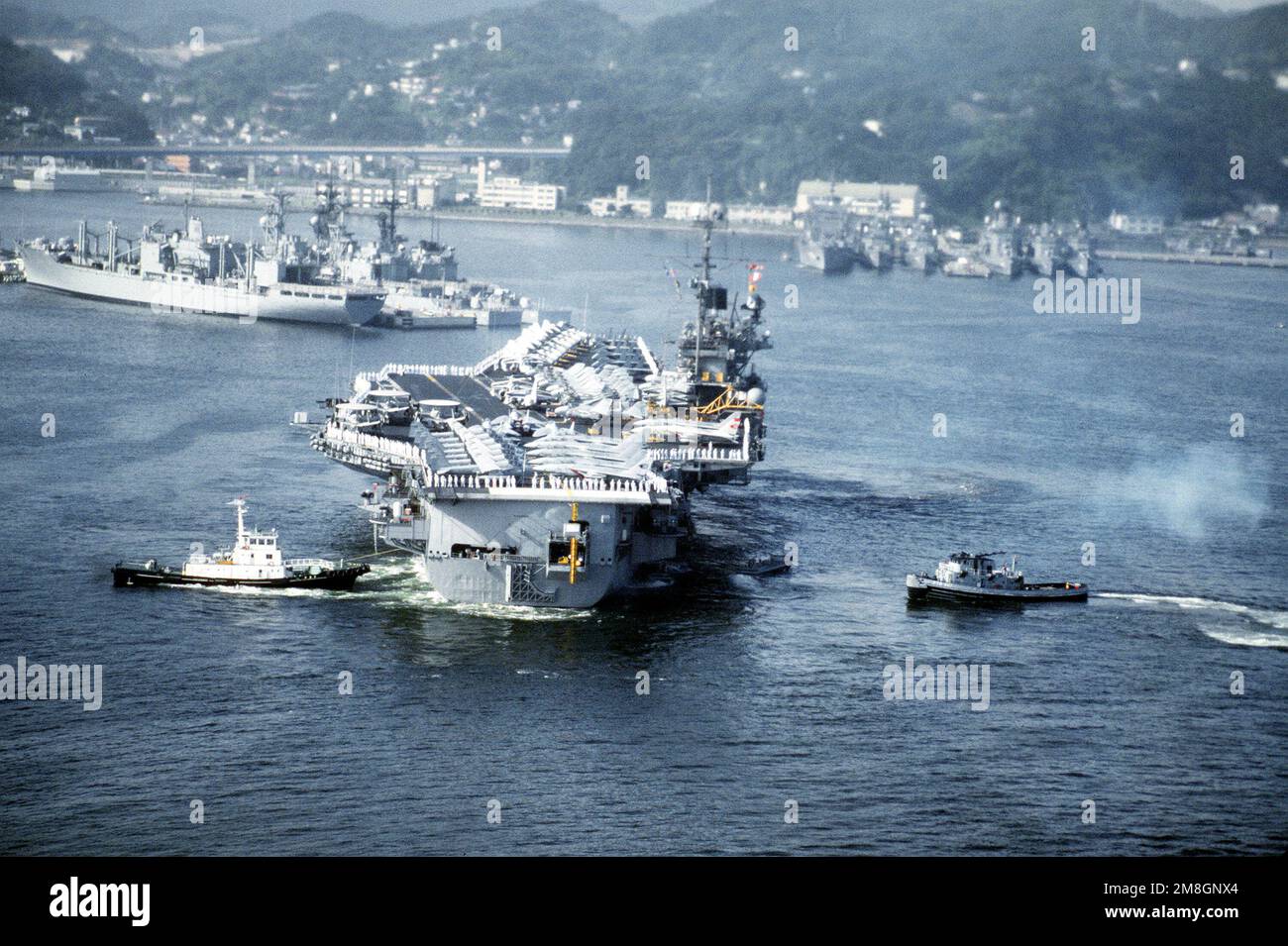 Large harbor tugs maneuver the aircraft carrier USS RANGER (CV-61) into ...
