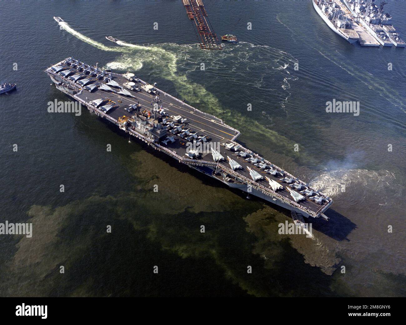 Large harbor tugs maneuver the aircraft carrier USS RANGER (CV-61) into ...