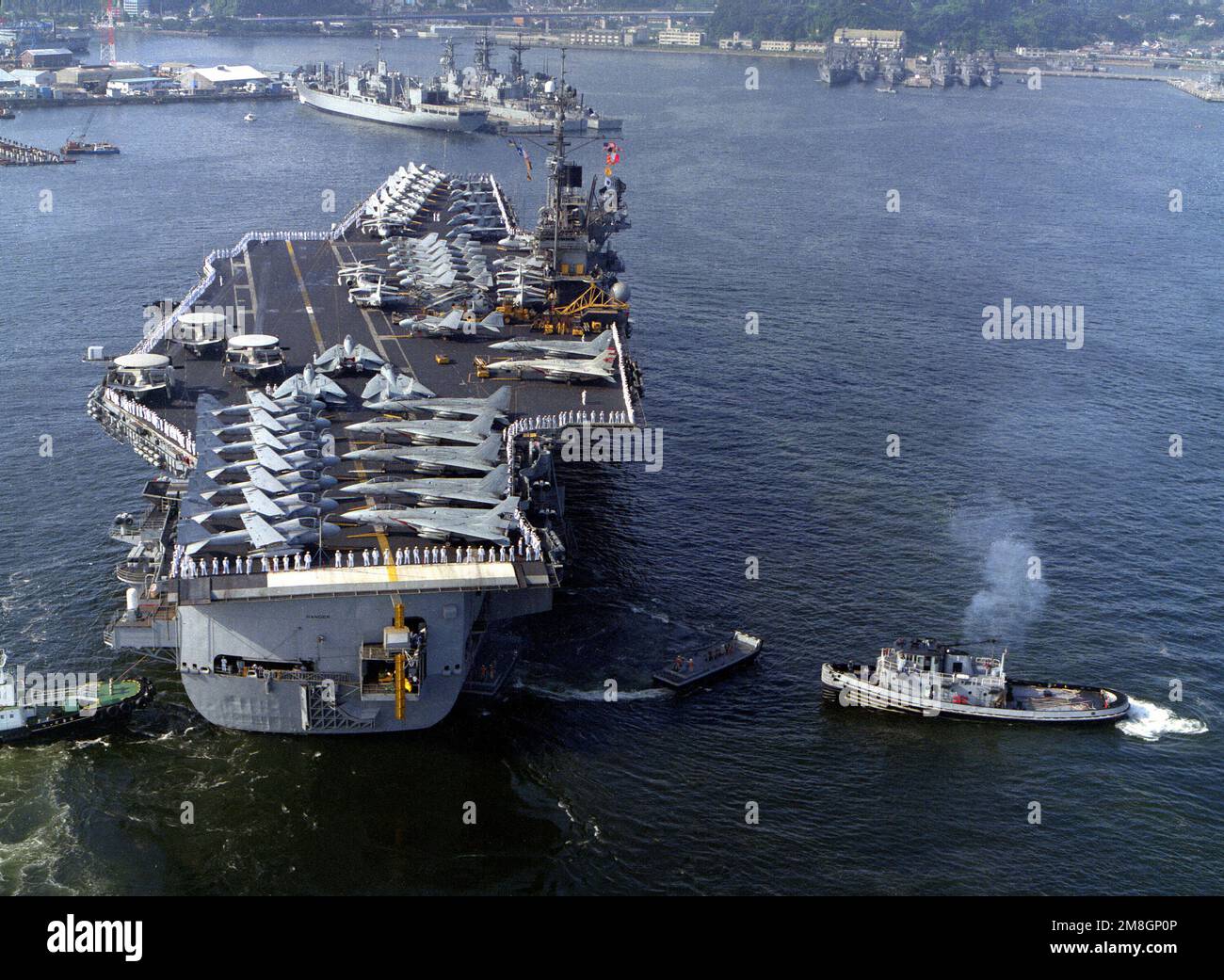 Large harbor tugs maneuver the aircraft carrier USS RANGER (CV-61) into ...