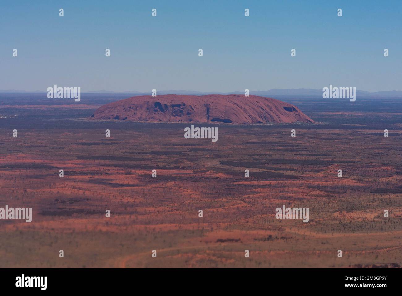 An aerial landscape of a deserted valley on the background of the Uluru ...