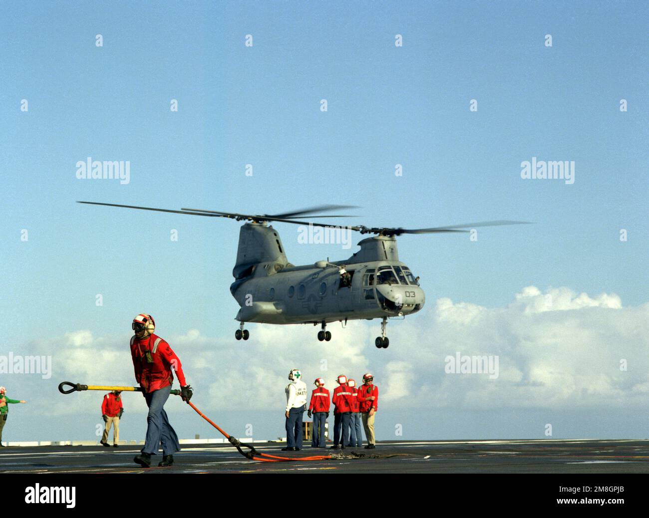 A CH-46 Sea Knight helicopter hovers over the flight deck of the ...