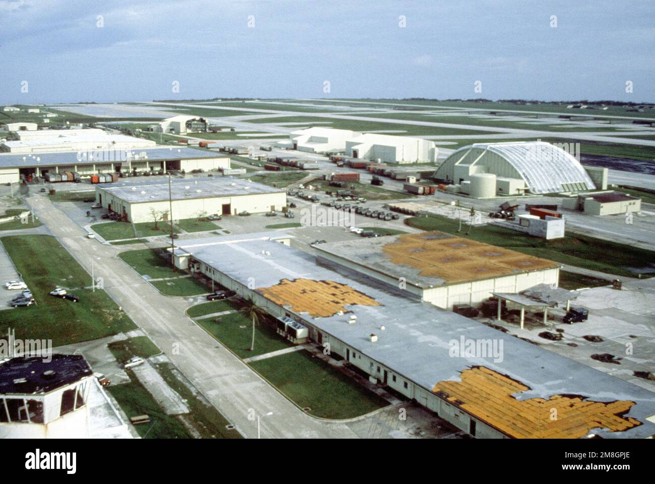 Overview of Anderson AFB flight line, with damaged roofs and battered ...