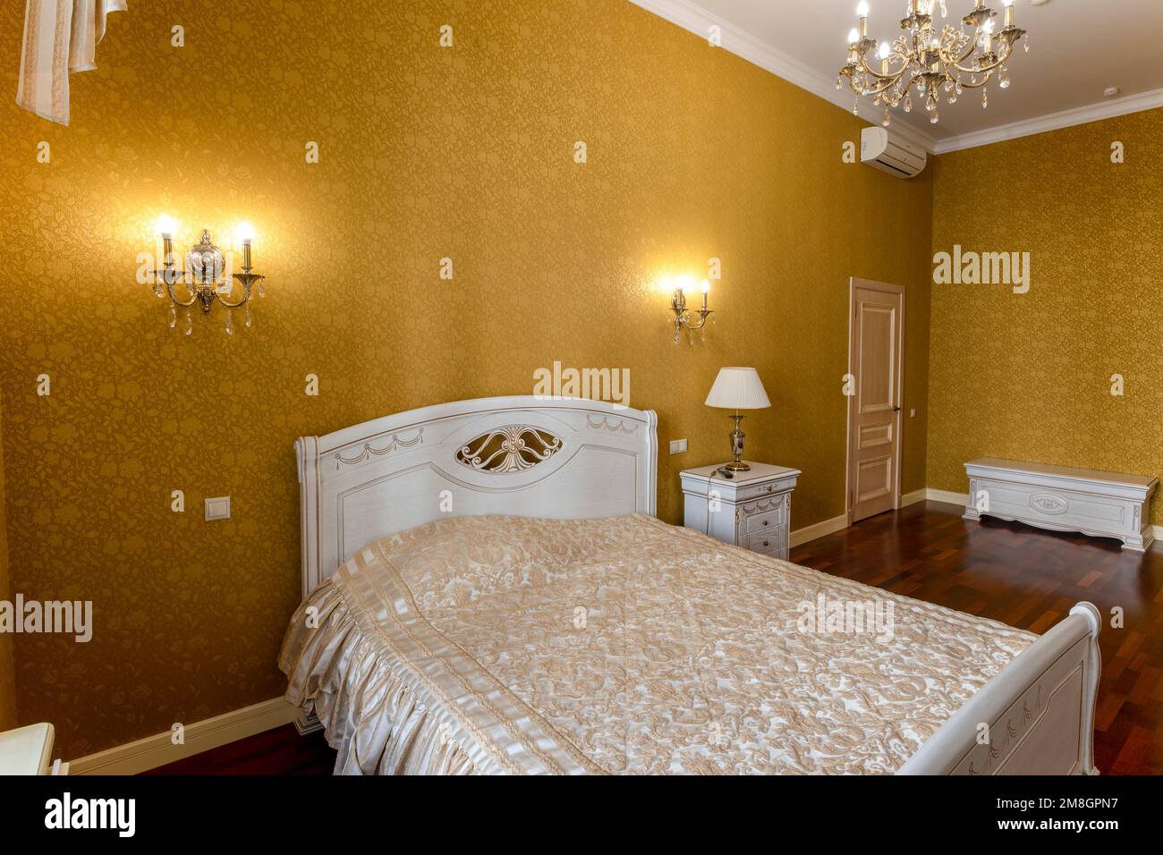 A large bright bedroom in yellow tones with a huge bed Stock Photo - Alamy