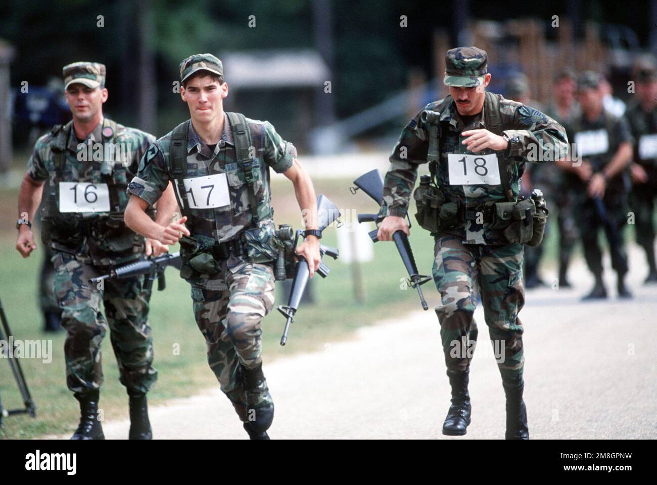 Participants carrying M-16 rifles run a three-mile combat course during ...
