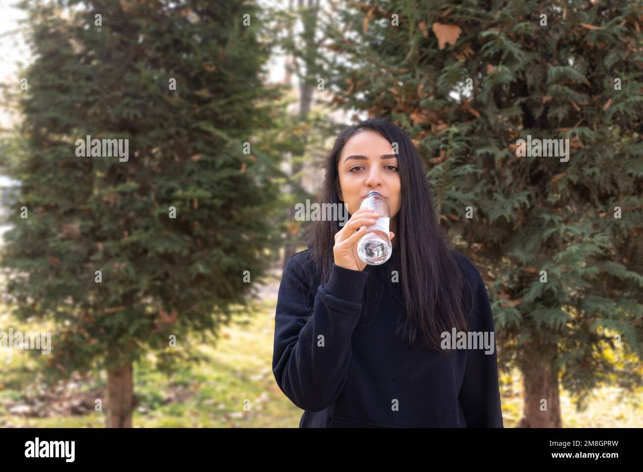 Woman drinking water. Caucasian millennial brunette woman standing at ...