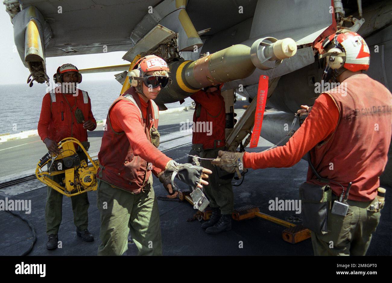 Aviation ordnancemen load a laser-guided bomb onto the pylon of an A-6E ...