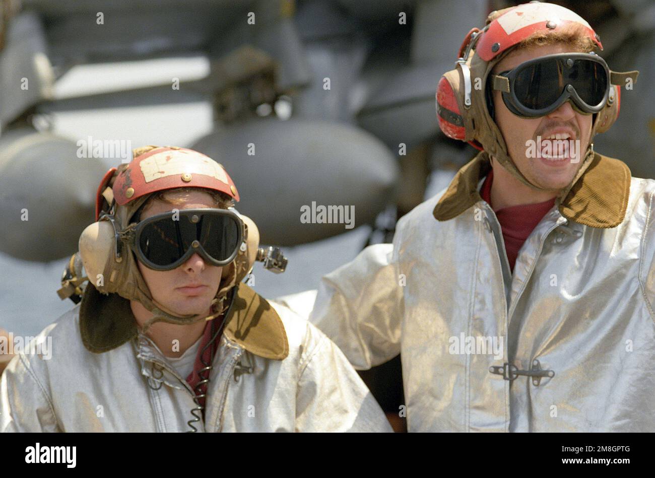 A flight deck crew member shouts instructions across the flight deck as ...