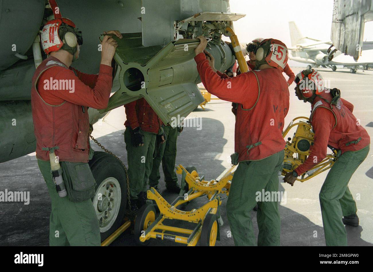 Aviation ordnancemen load a laser-guided bomb onto the pylon of an A-6E ...