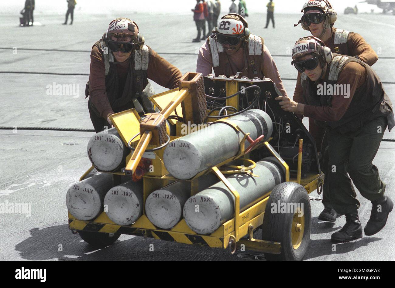 Flight deck crew members move a NAN-2 nitrogen servicing unit across ...