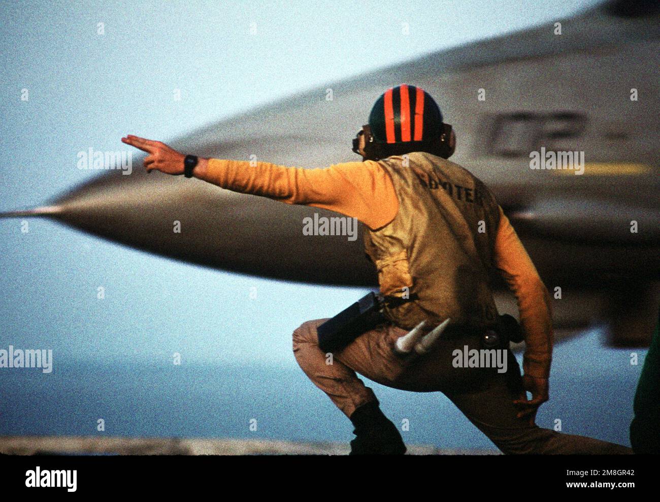 The launch officer gives the launch signal to the pilot of an F-14 ...
