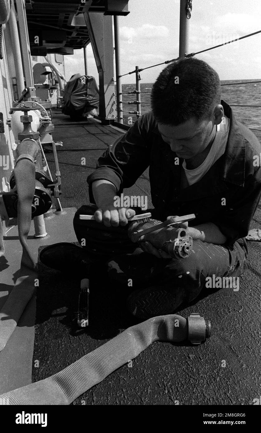A crewman cleans a hose fitting aboard the guided missile frigate USS ...