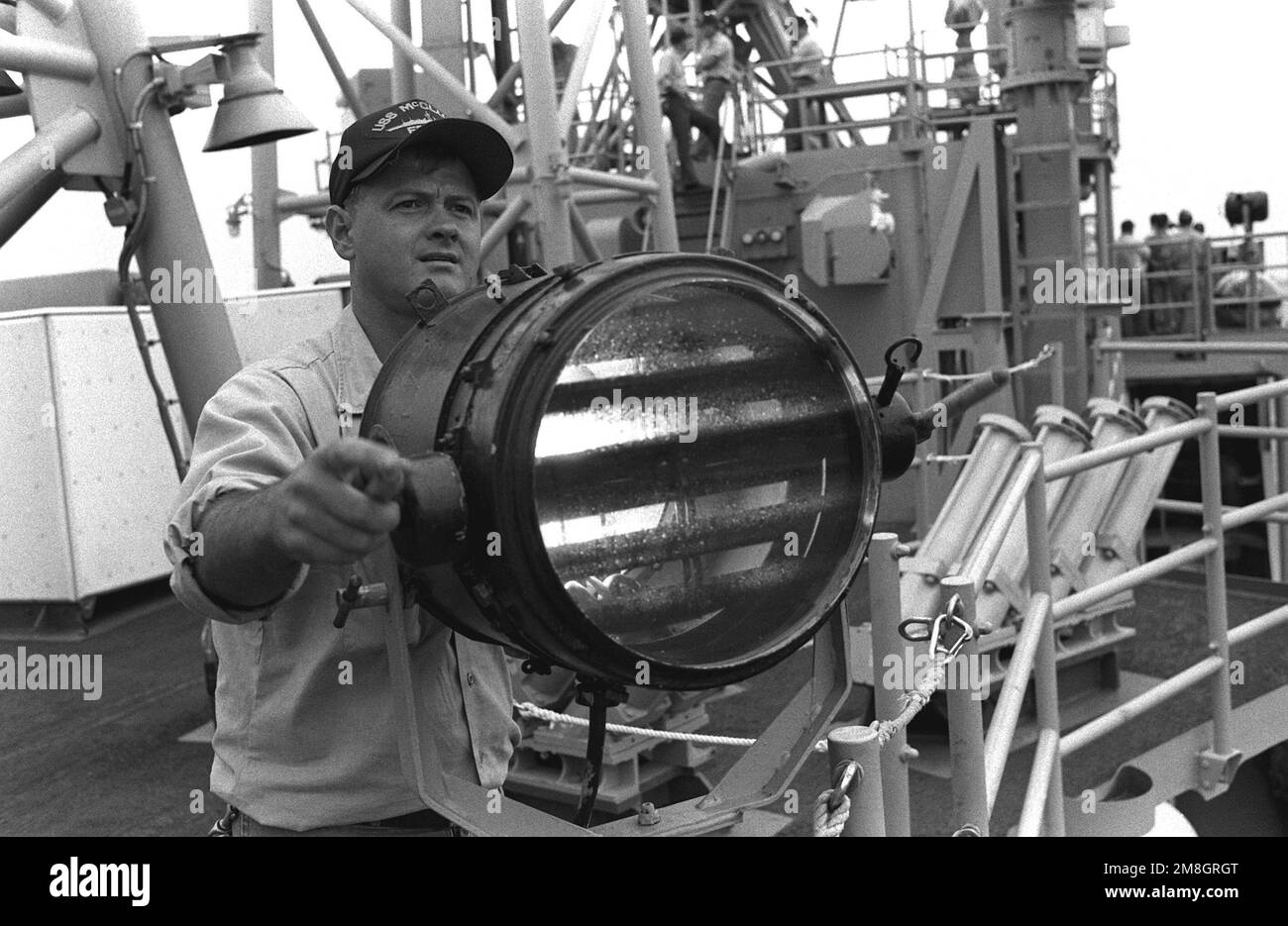 A signalman operates a signal searchlight aboard the guided missile ...