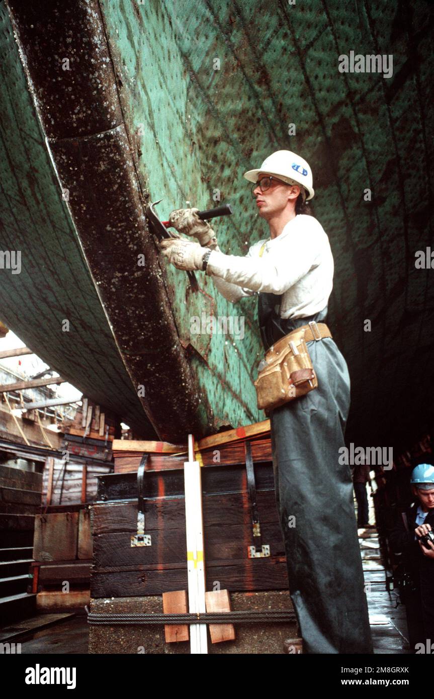 A worker begins removing the copper sheathing from the hull of the 44 ...