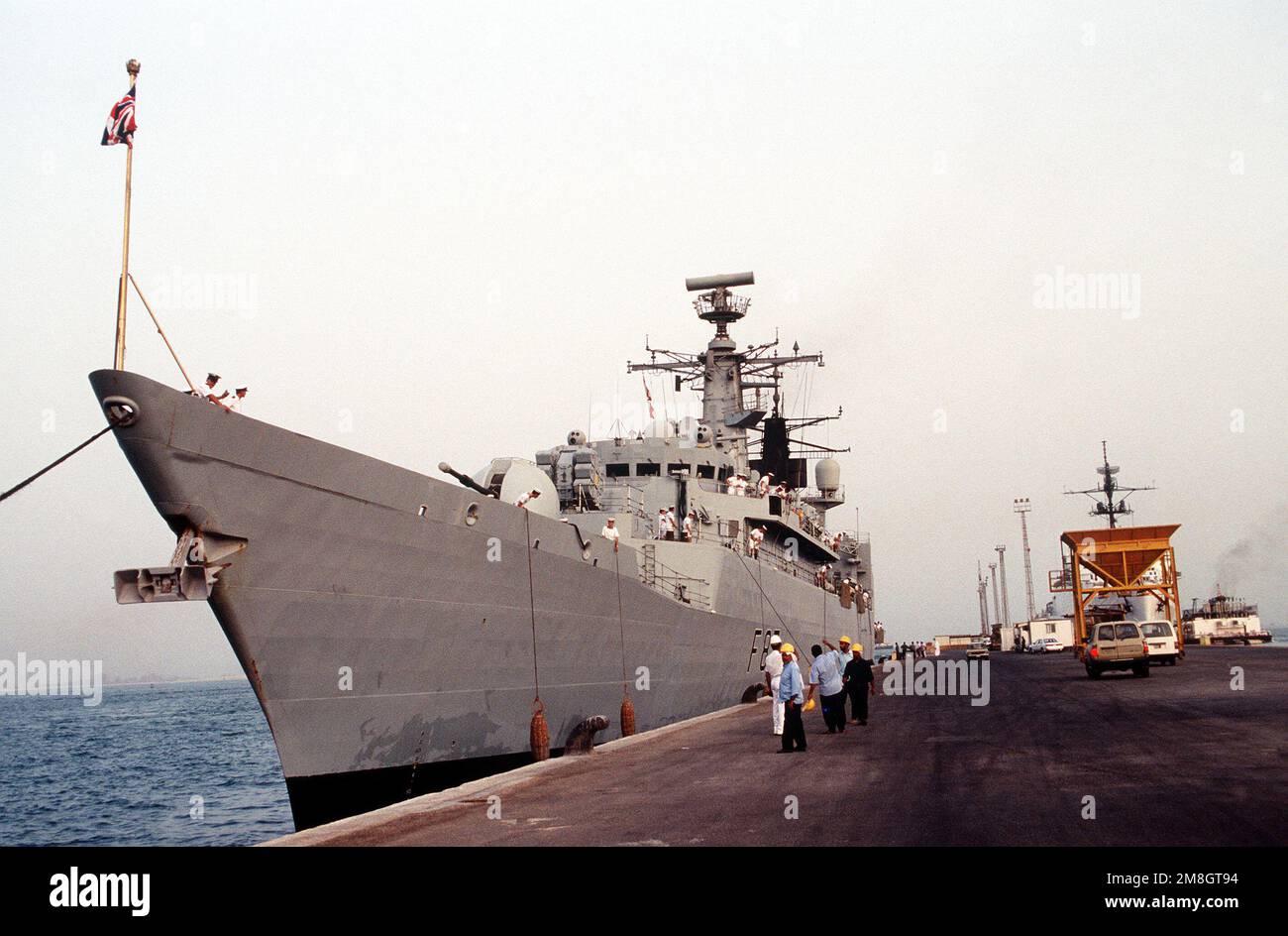 Dock workers stand beside the British frigate HMS CHATHAM (F-87 ...
