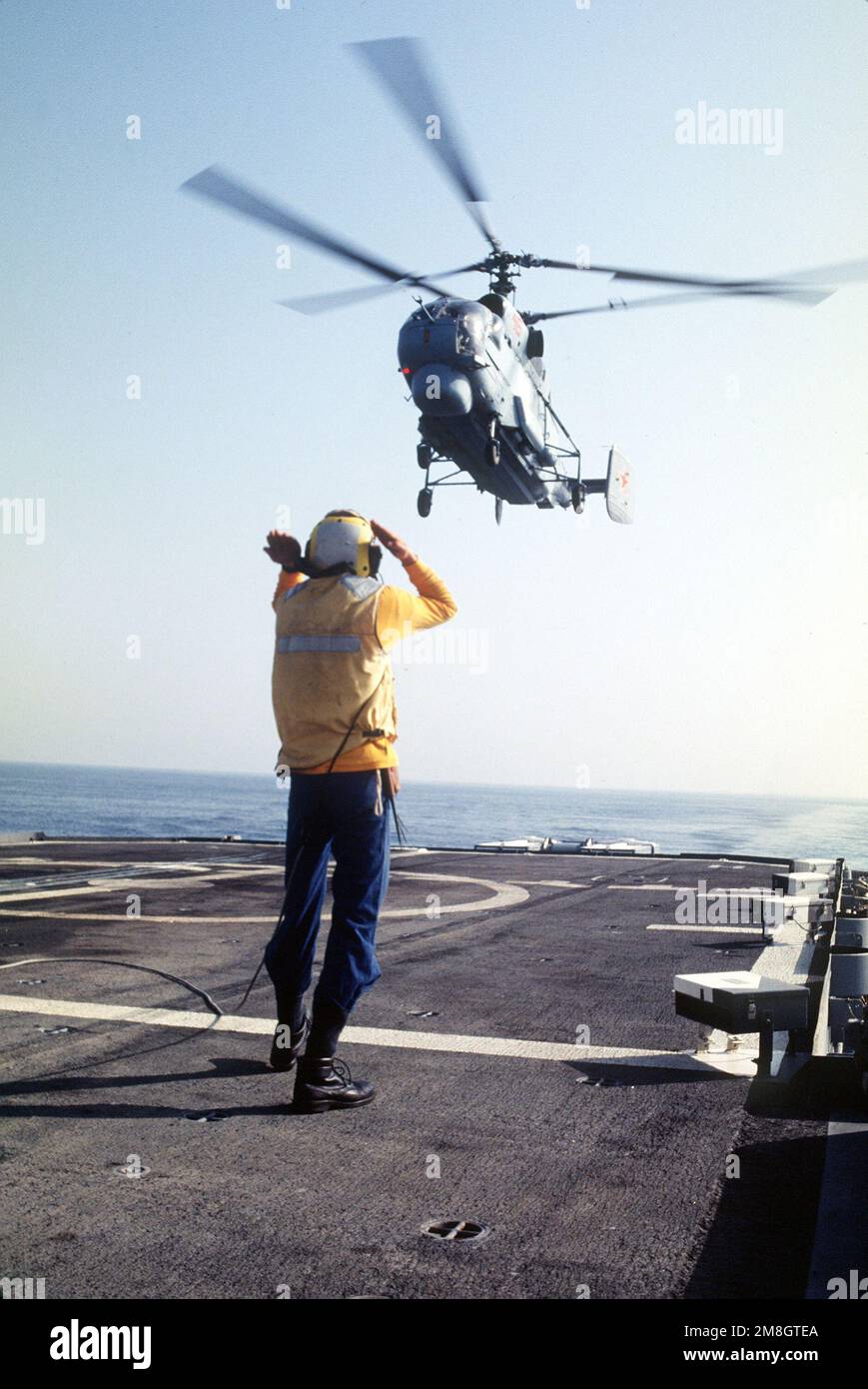 A crew member aboard the destroyer USS KINKAID (DD-965) signals to the ...