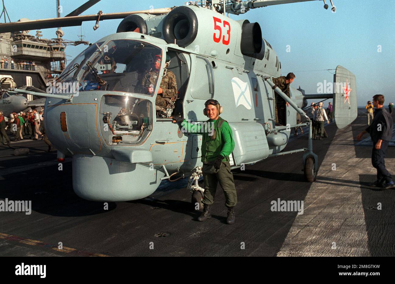 A flight deck crew member stands beside a Russian Ka-27 Helix ...