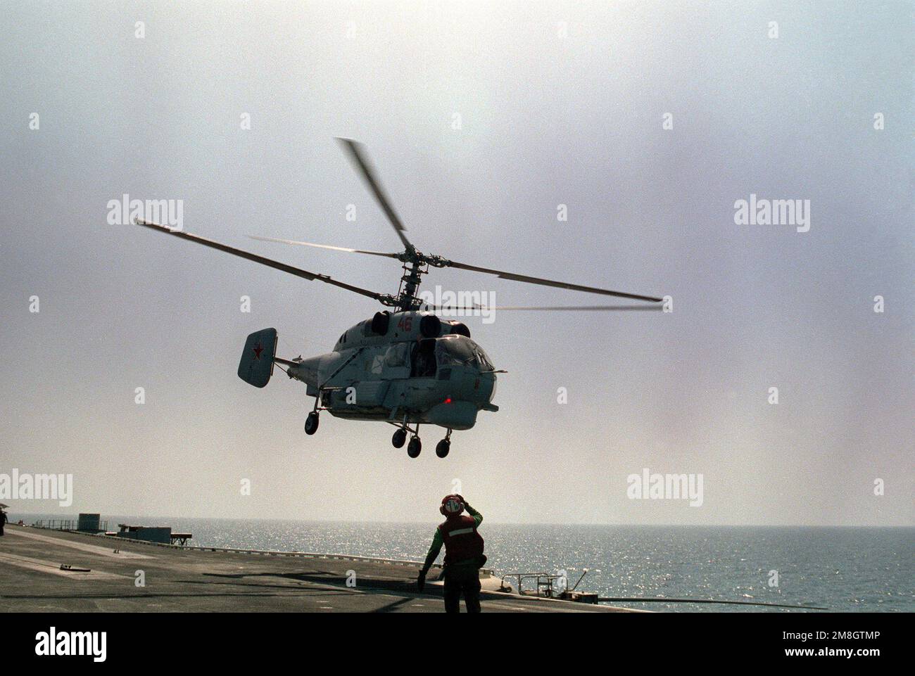 A flight deck crew member signals to the pilot of a Russian Ka-27 Helix ...