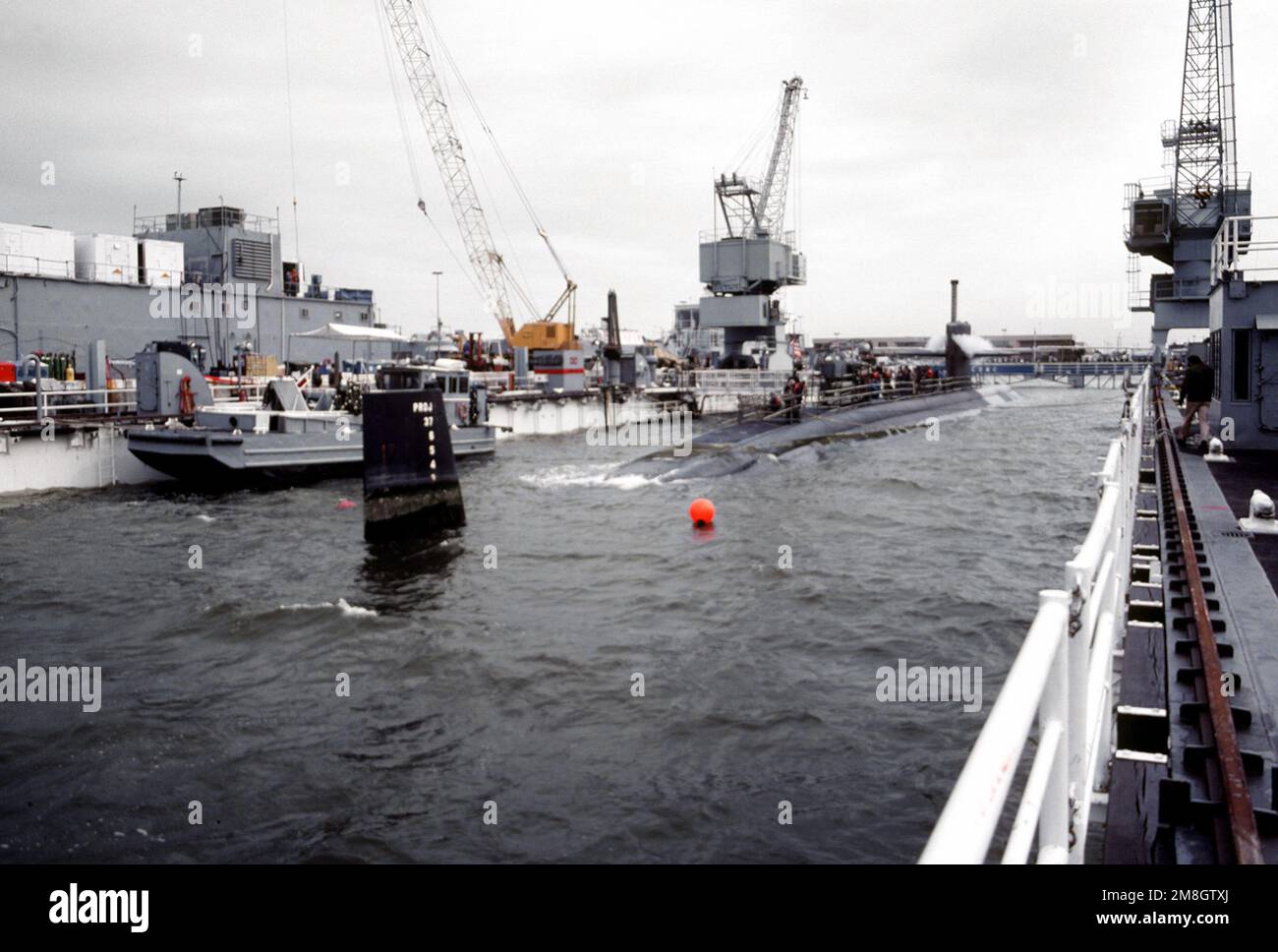 Crewmen inspect mooring lines positioning the nuclear-powered attack ...