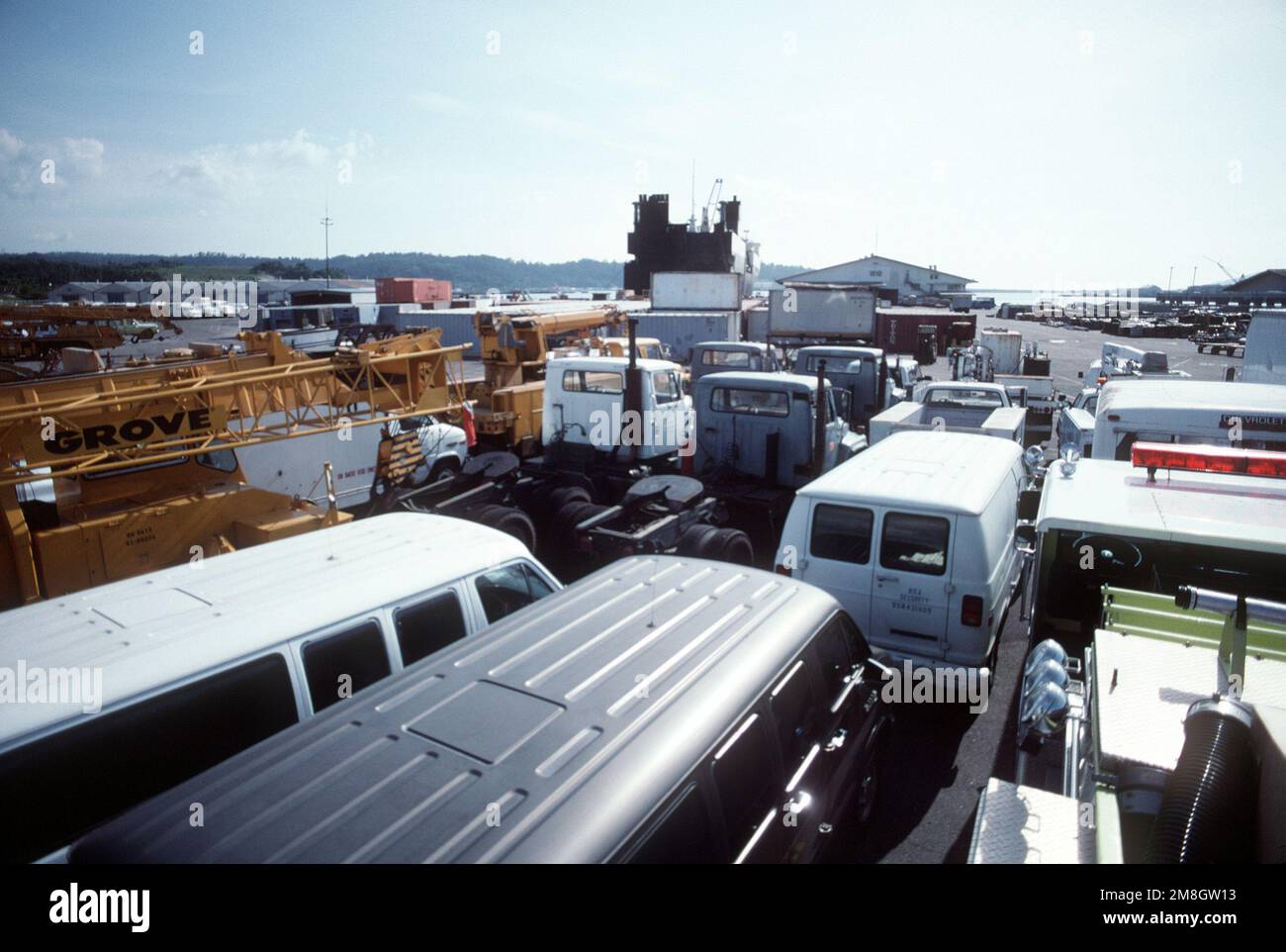 Government vehicles are parked in a holding area for loading aboard the ...
