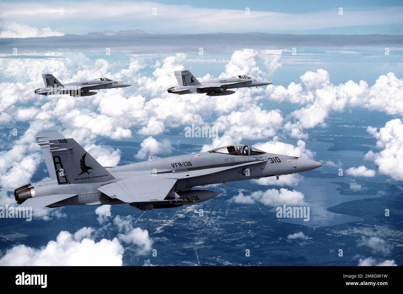 An air-to-air, right side view of three Strike Fighter Squadron 136 ...