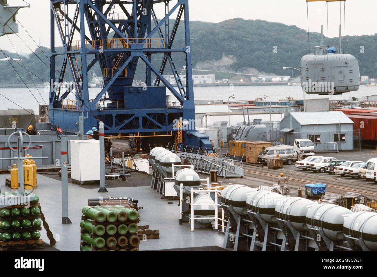A civilian worker guides a Mark 33 3-inch/50-caliber gun turret being ...