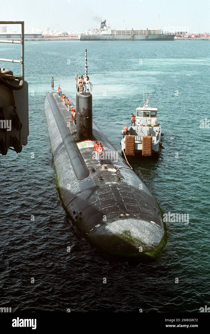 A yard craft assists the nuclear-powered attack submarine USS TOPEKA ...