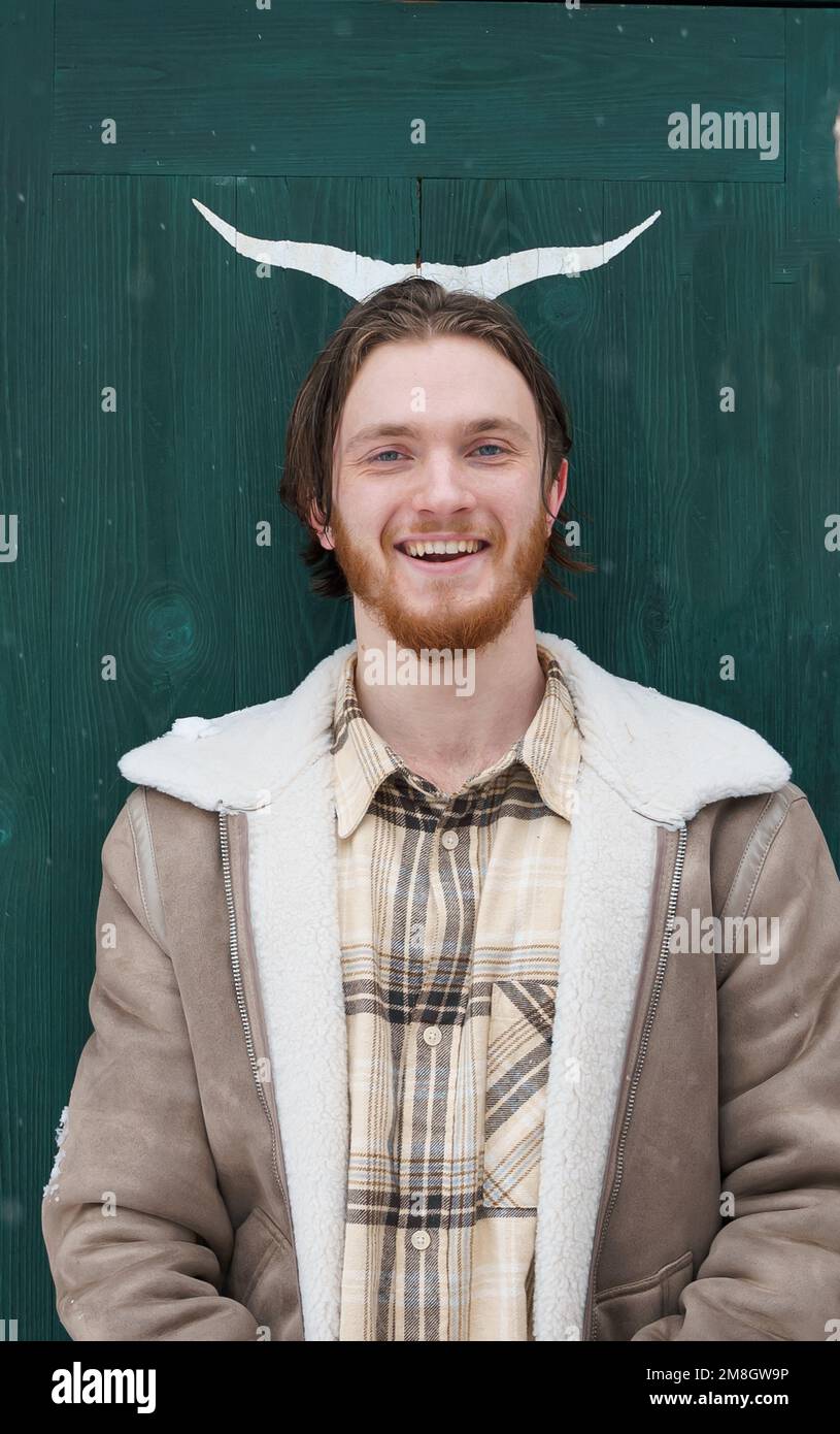 Young guy walking near red barn,green door.Deer,elk,bull antlers ...