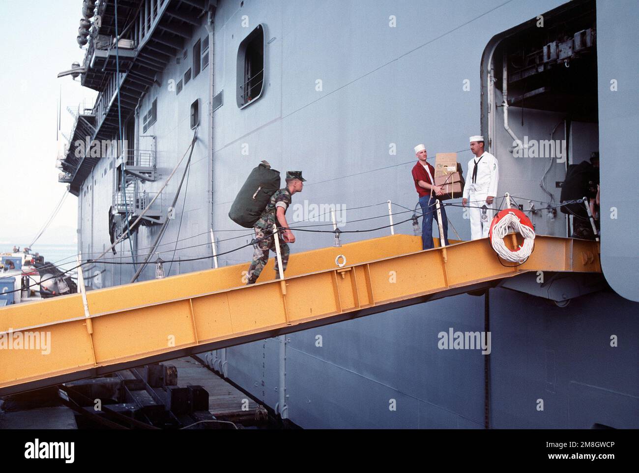 A Marine boards the amphibious assault ship USS BELLEAU WOOD (LHA-3) as ...