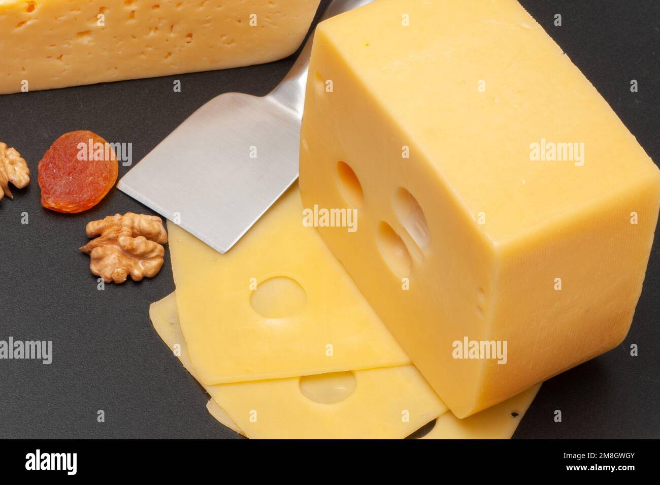 Different types of cheese on a wooden board decorated with grapes ...