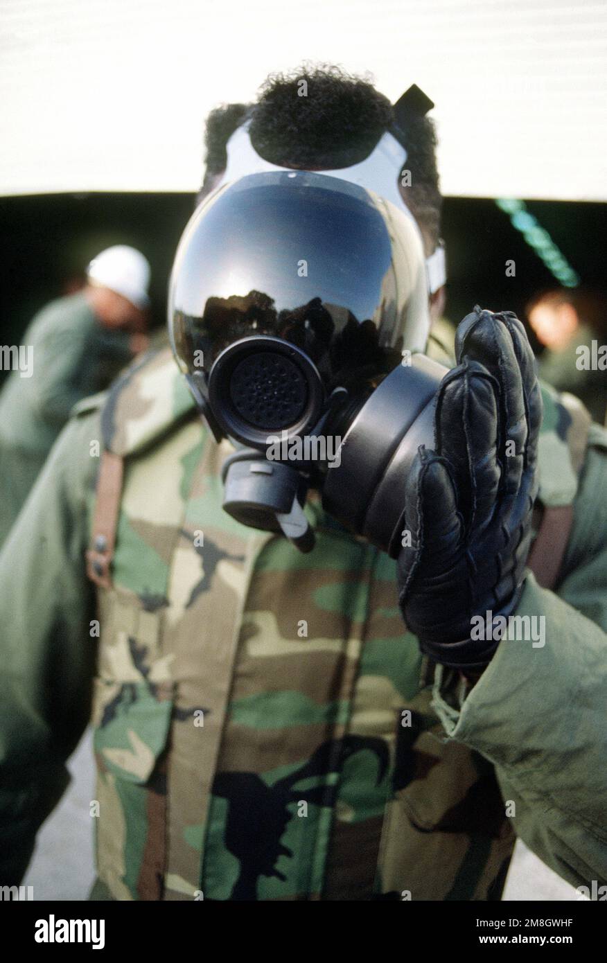 Yeoman 2nd Class George Oliver checks the fit of his gas mask while ...