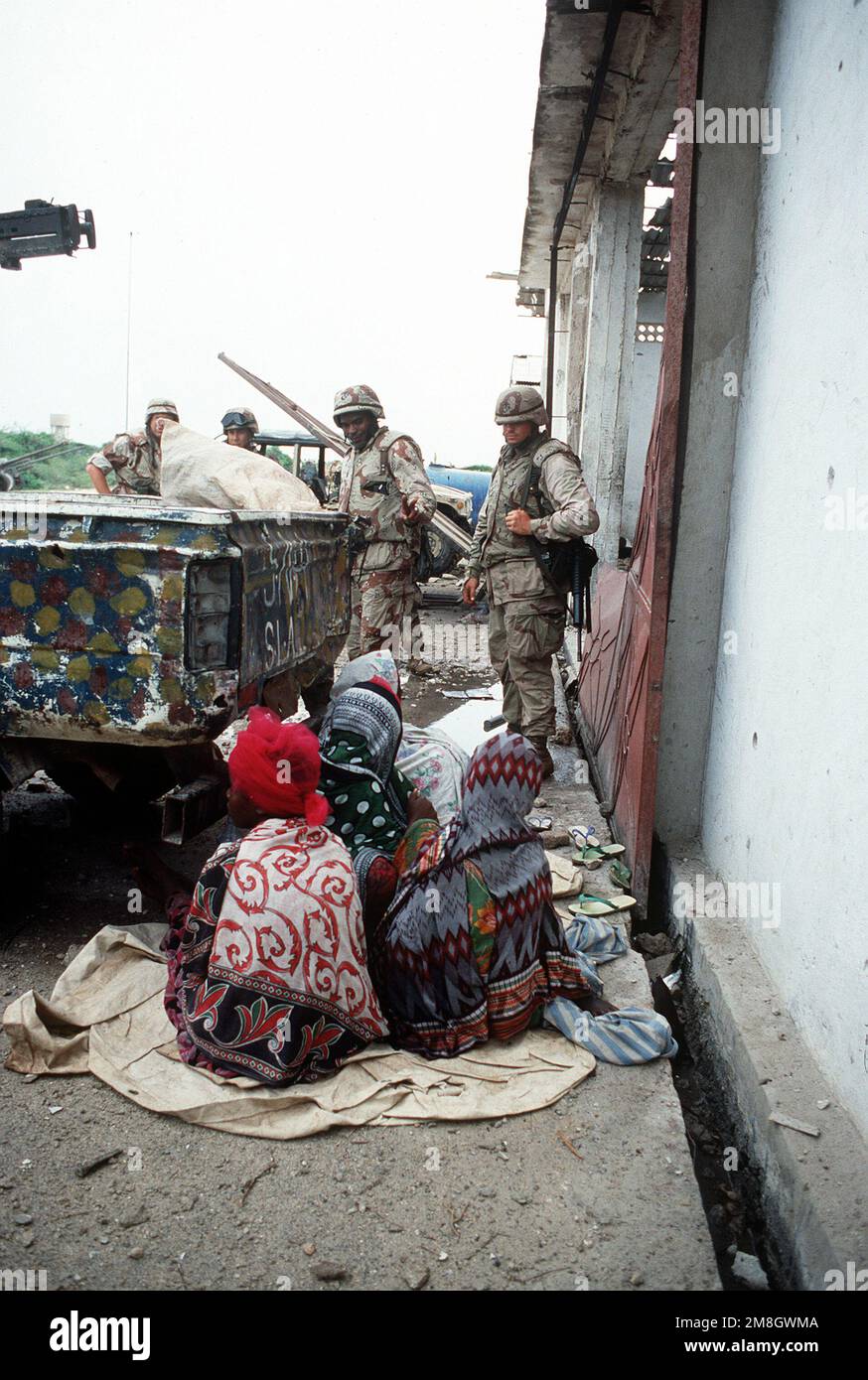 A Marine gestures to a group of Somali women sitting behind a truck ...