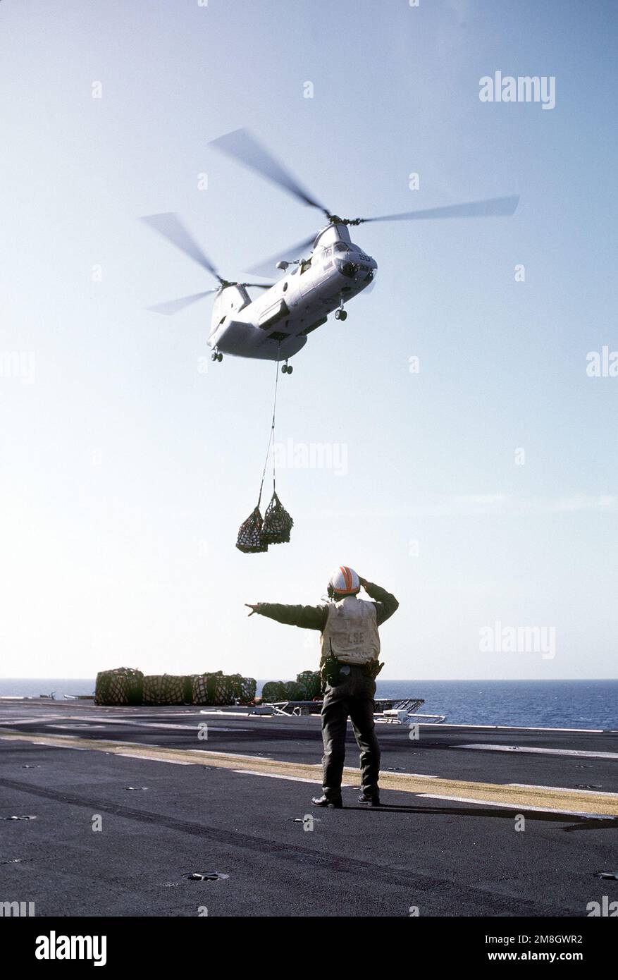 A crew member signals to the pilot of a UH-46D Sea Knight helicopter as ...