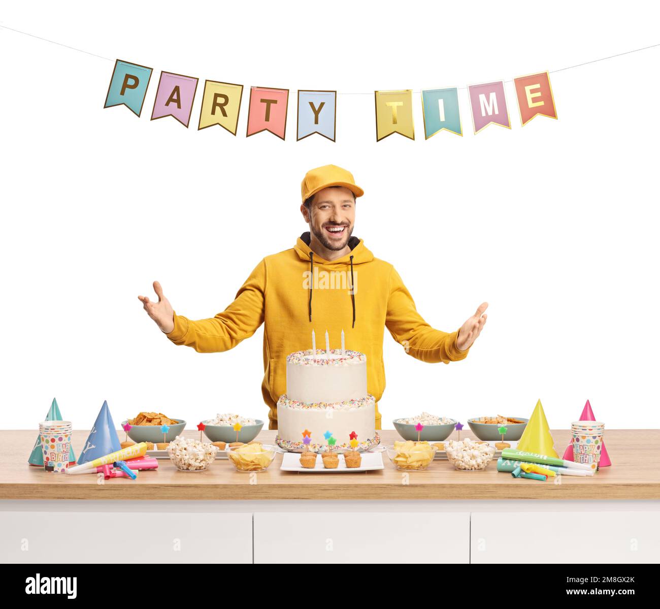 Guy gesturing with hands behind a counter with party snacks and a cake ...
