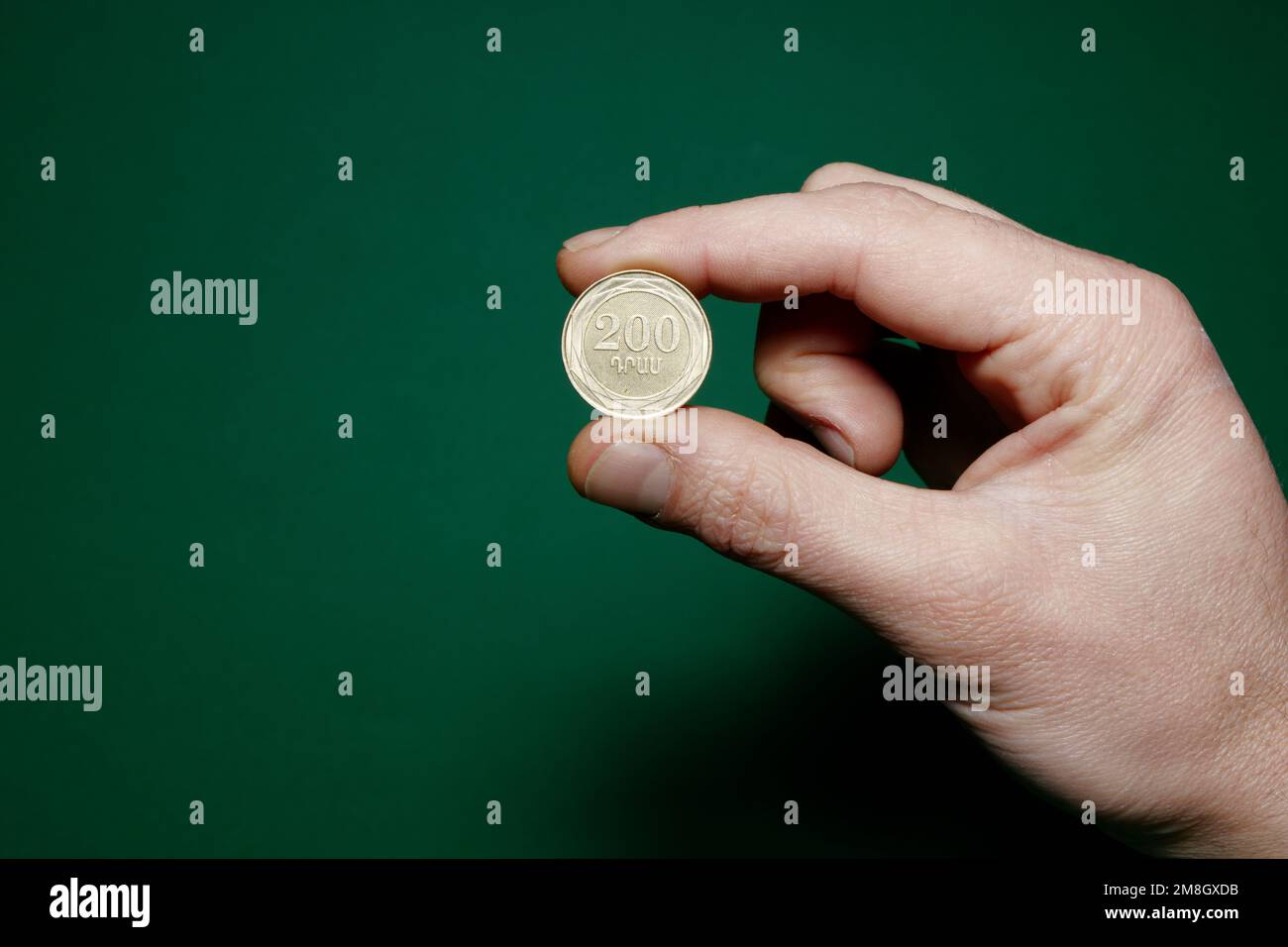 200 dram coin pinched with fingers on a green background Stock Photo ...