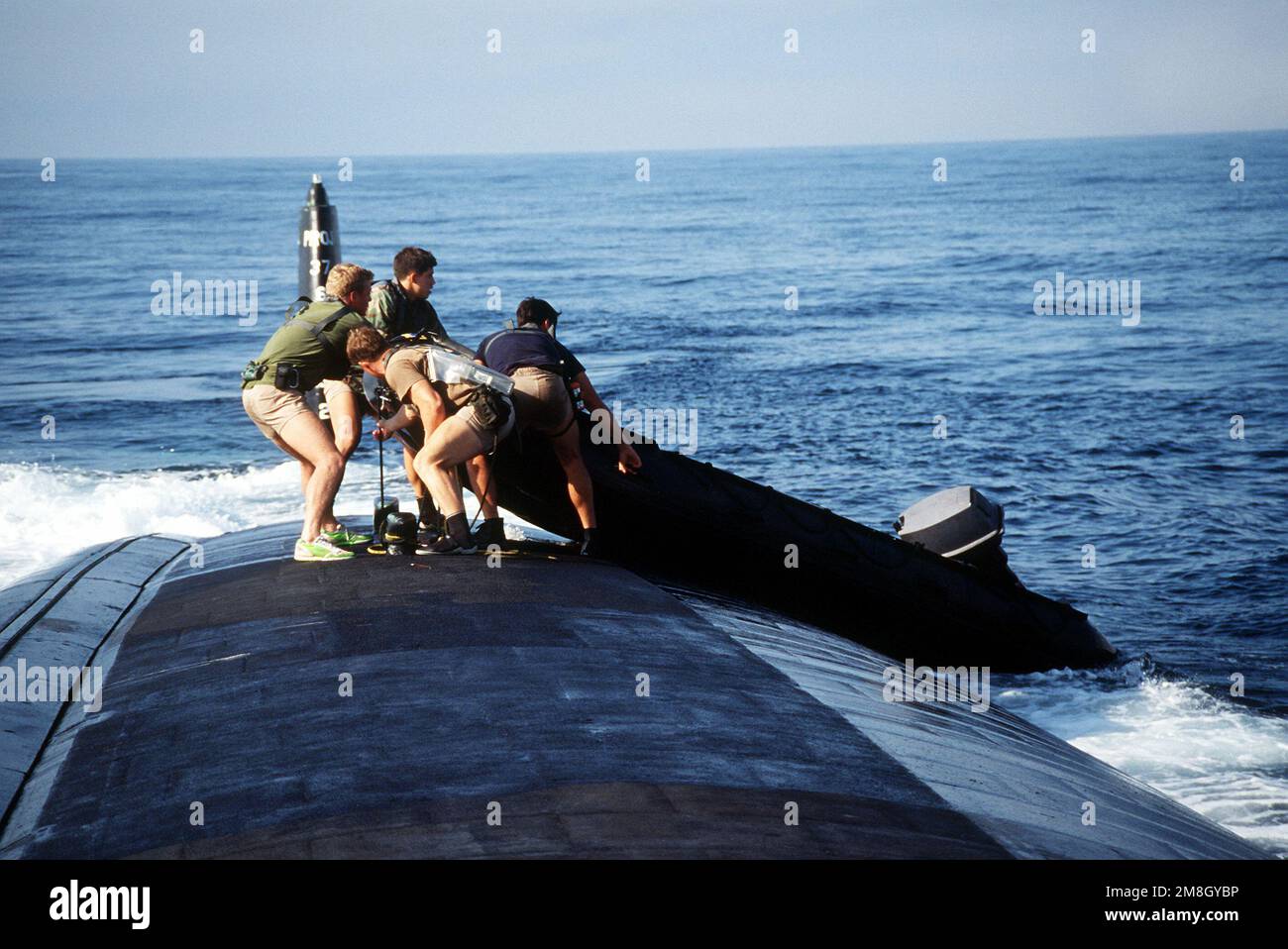 Four members of SEAL Team One are shown recovering a Zodiac boat on the ...