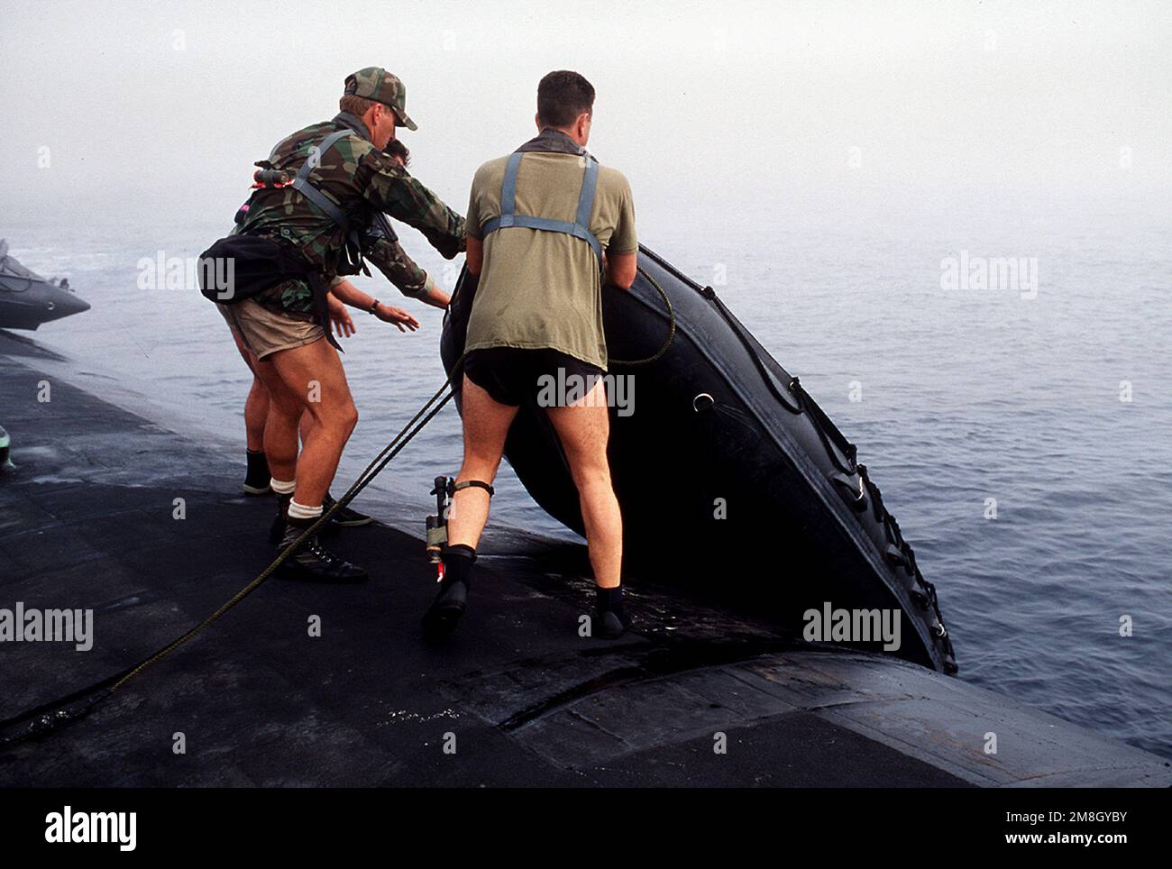 Navy divers from SEAL Team One are show launching a Zodiac boat from ...