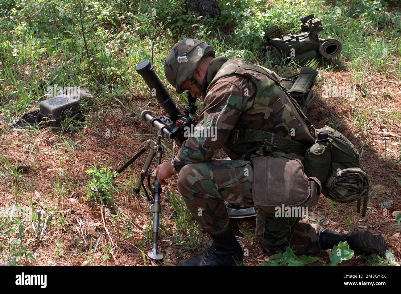 A Marine kneels while looking through the sight of an M224 60MM mortar ...