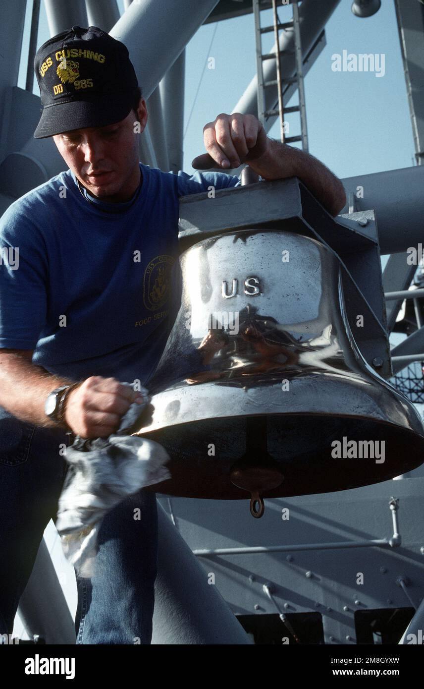 A sailor polishes the ship's bell aboard the destroyer USS CUSHING (DD ...
