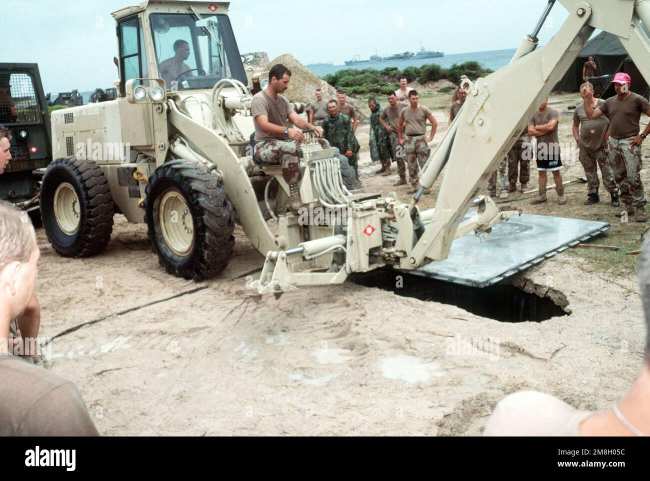 Members of Naval Mobile Construction Battalion 40 use an excavator ...
