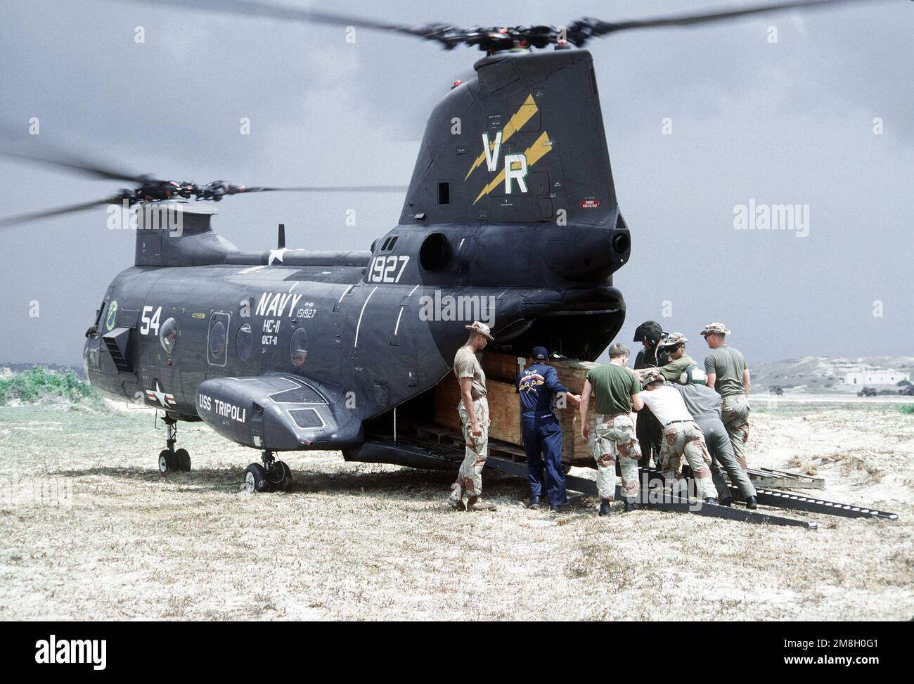 Members of the USS Tripoli (LPH-10) beach detachment push a pallet of ...