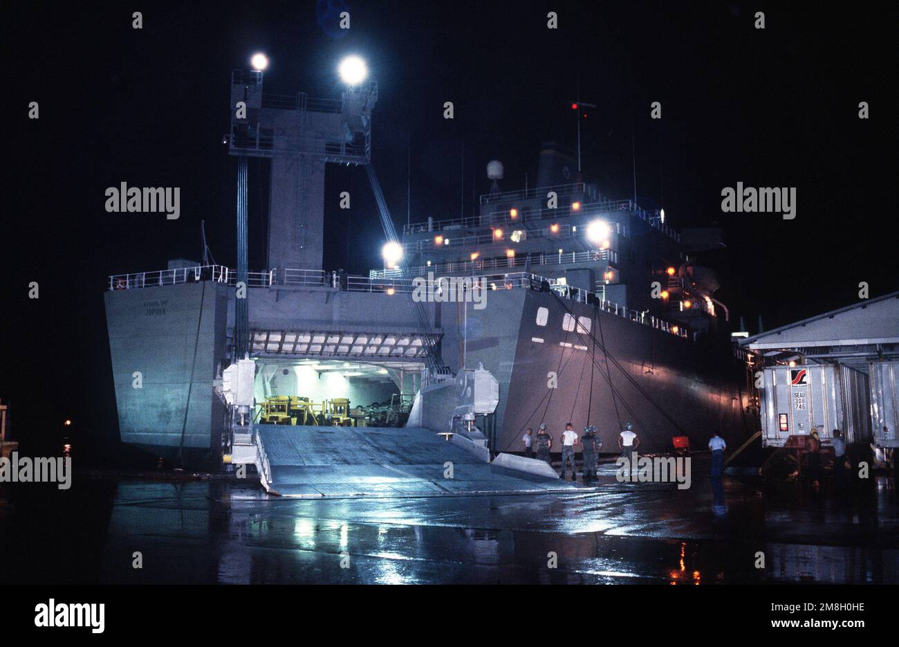 Workers stand by to unload the vehicle cargo ship USNS JUPITER (T-AKR-11). Base: Naval Supply ...