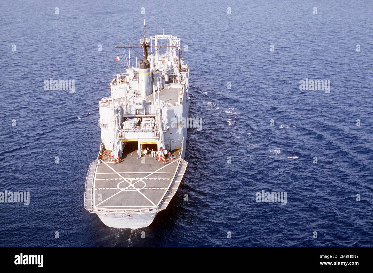 Flight deck personnel stand by as a helicopter approaches the ...